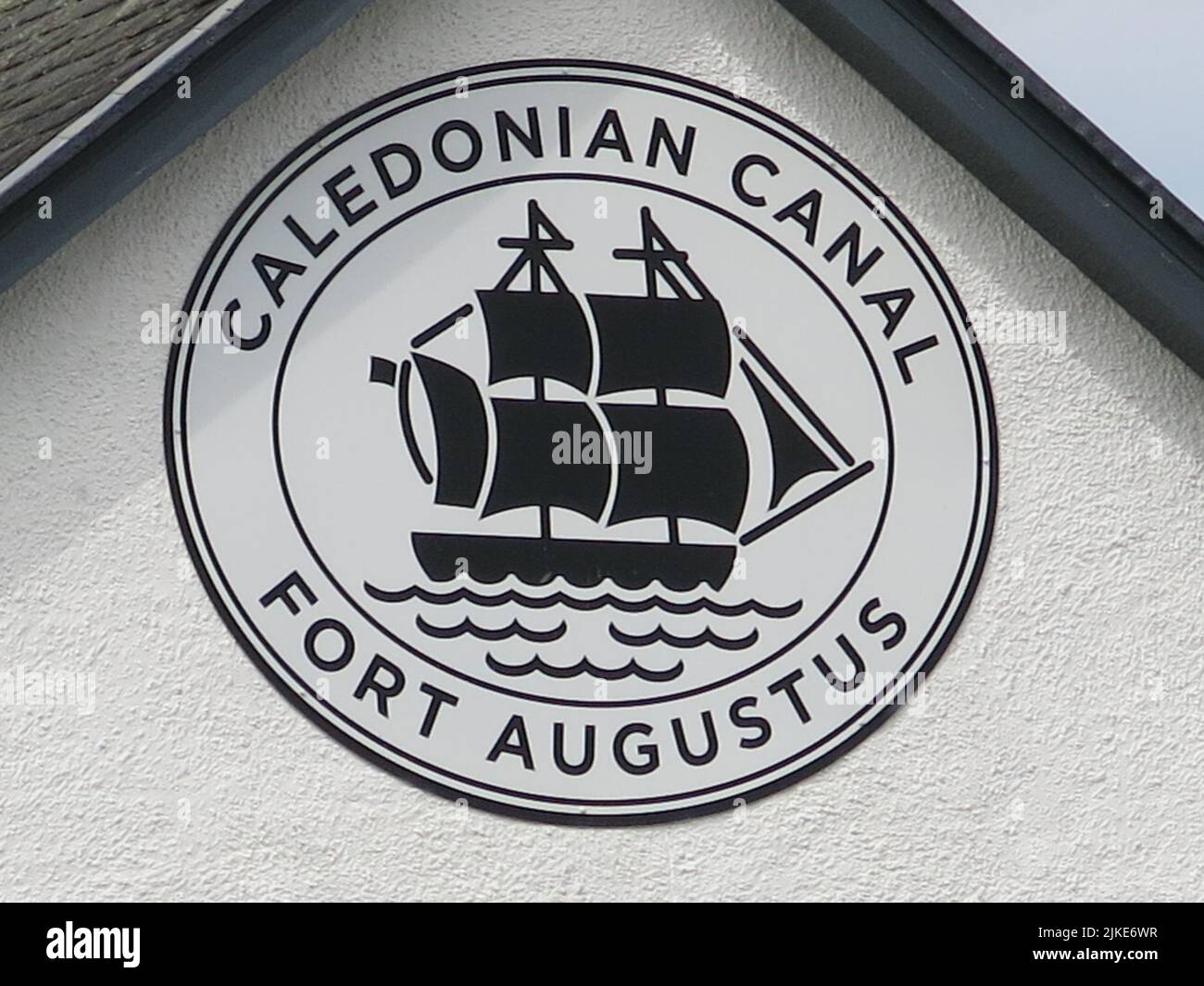 An oval-shaped sign on a building with an image of a sailing ship on ...