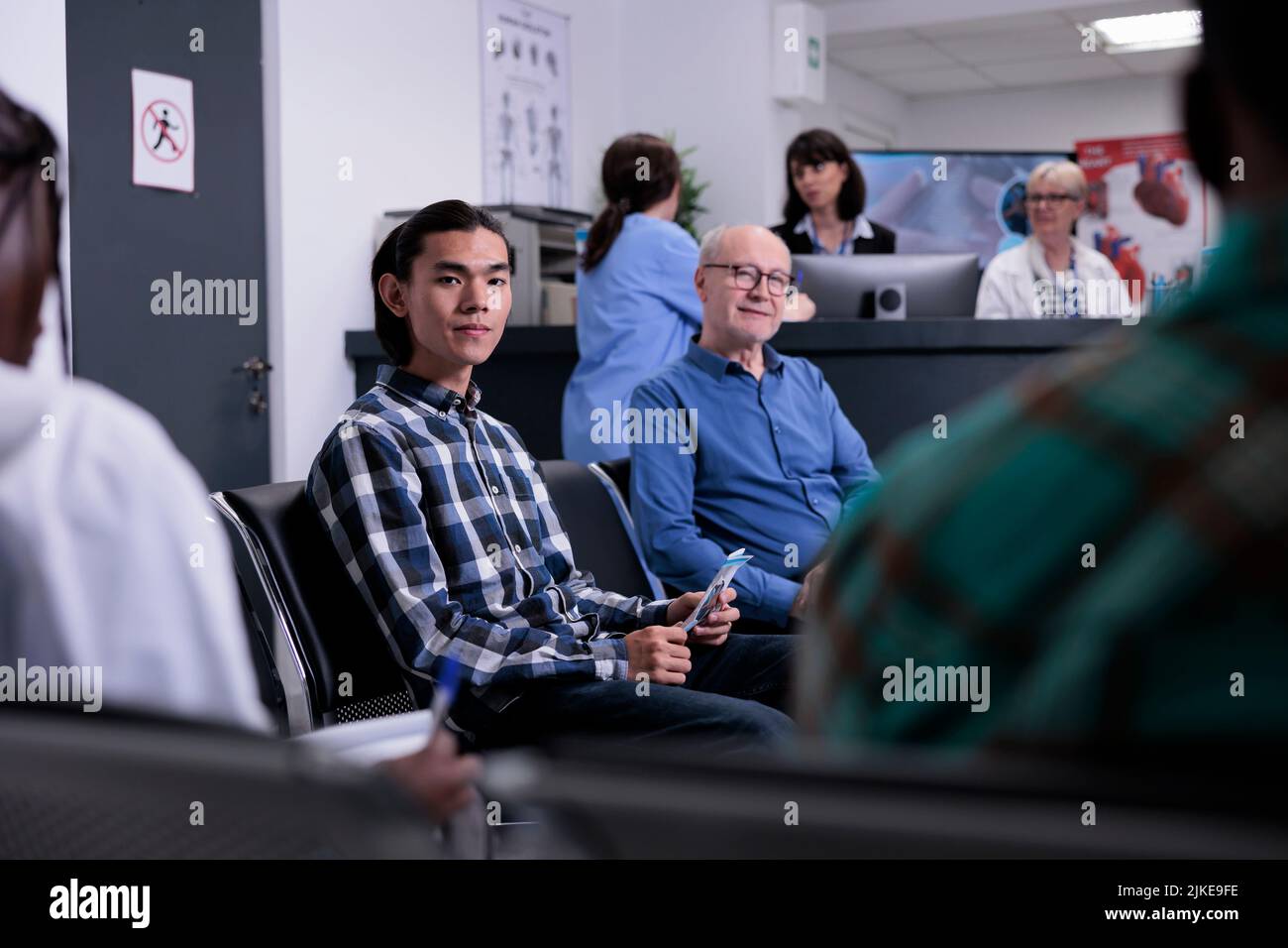 Portrait of asian patient in hospital reception lobby, sitting in ...