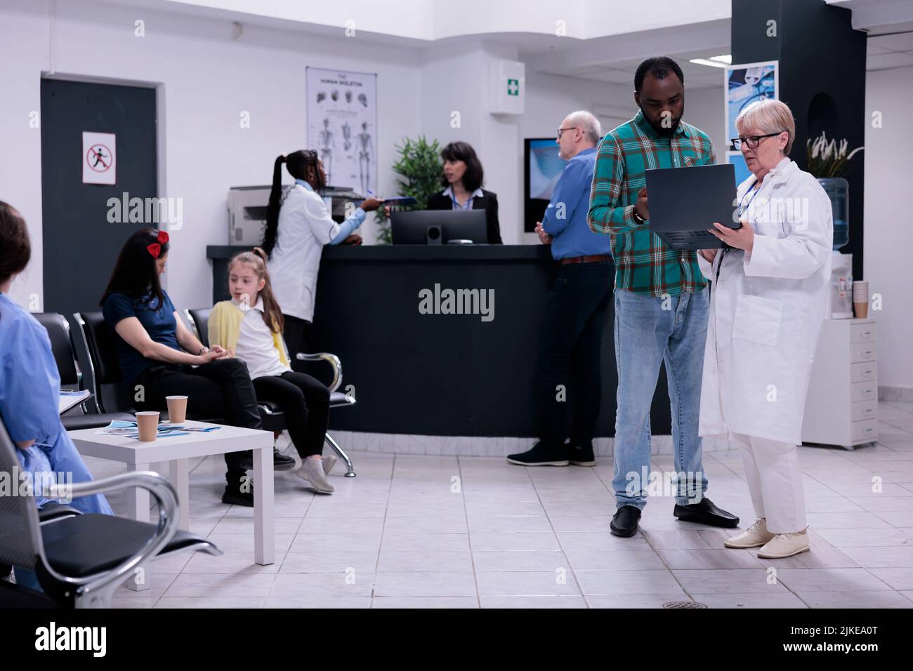 Senior medic holding laptop with lab results talking with african ...