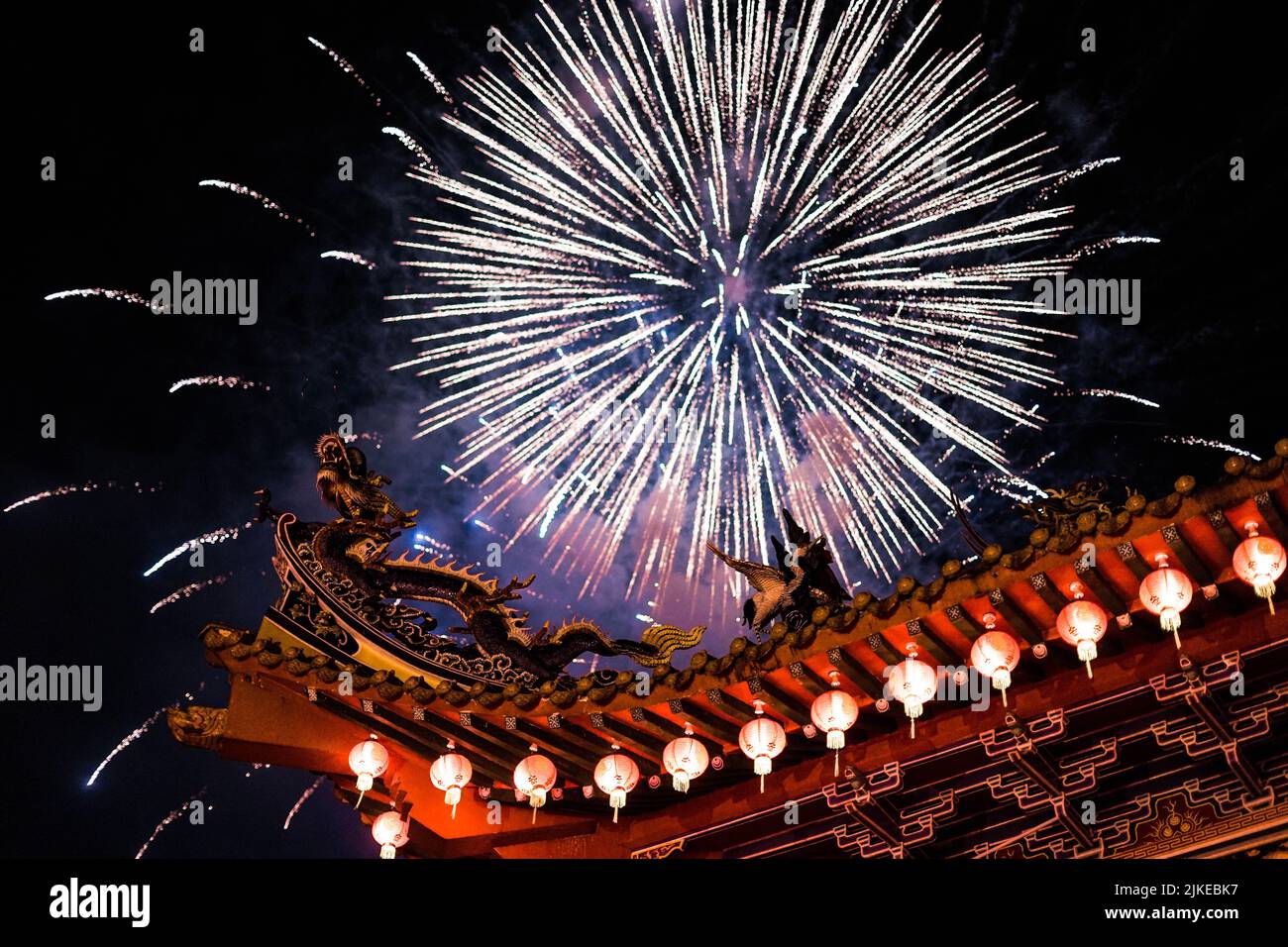 A low angle shot of exploding fireworks over a Chinese building roof ...