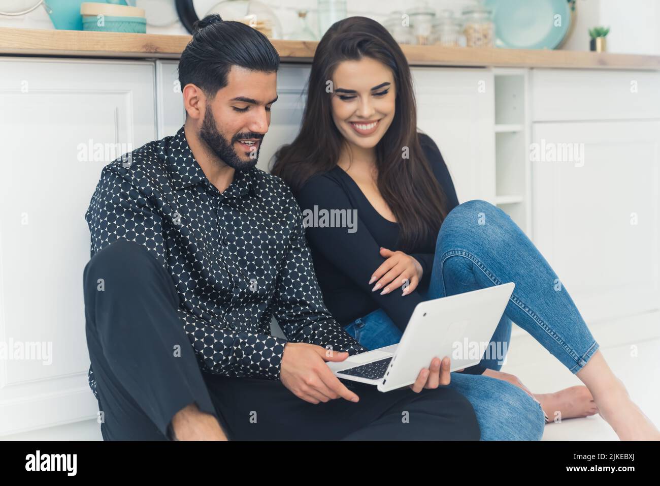 Woman with long dark hair smiling looking at laptop on her boyfriend's ...