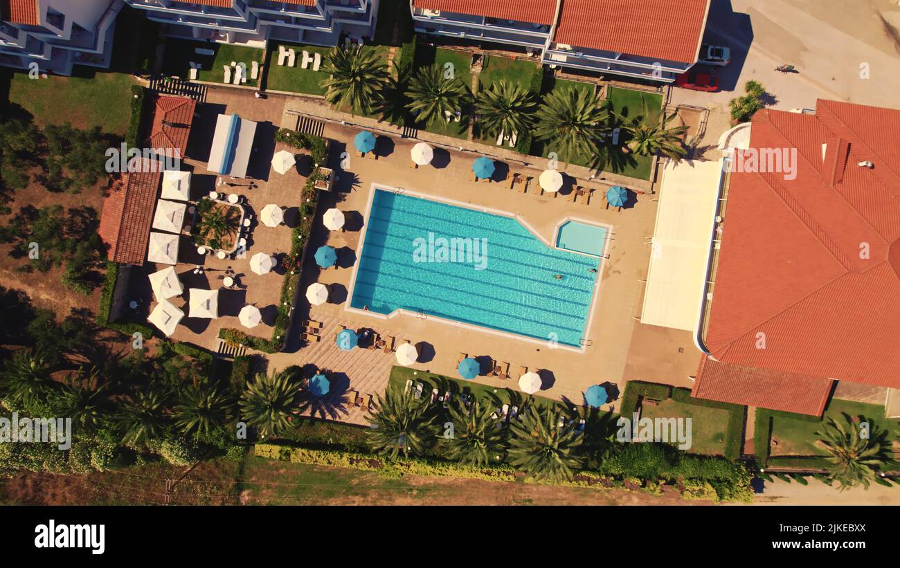 Top view of a small hotel pool with white and blue umbrellas standing ...