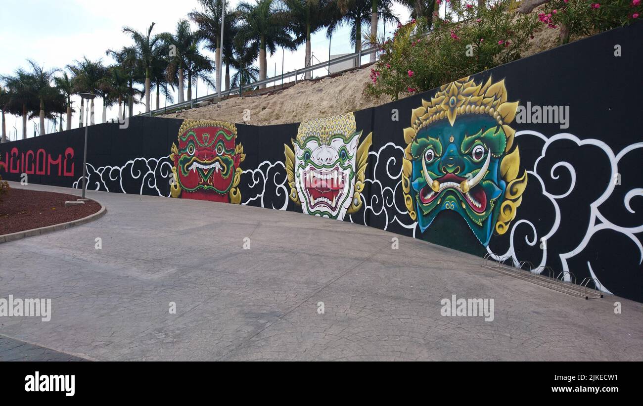 A street art of Japanese dragons heads on a long wall on a sunny day ...