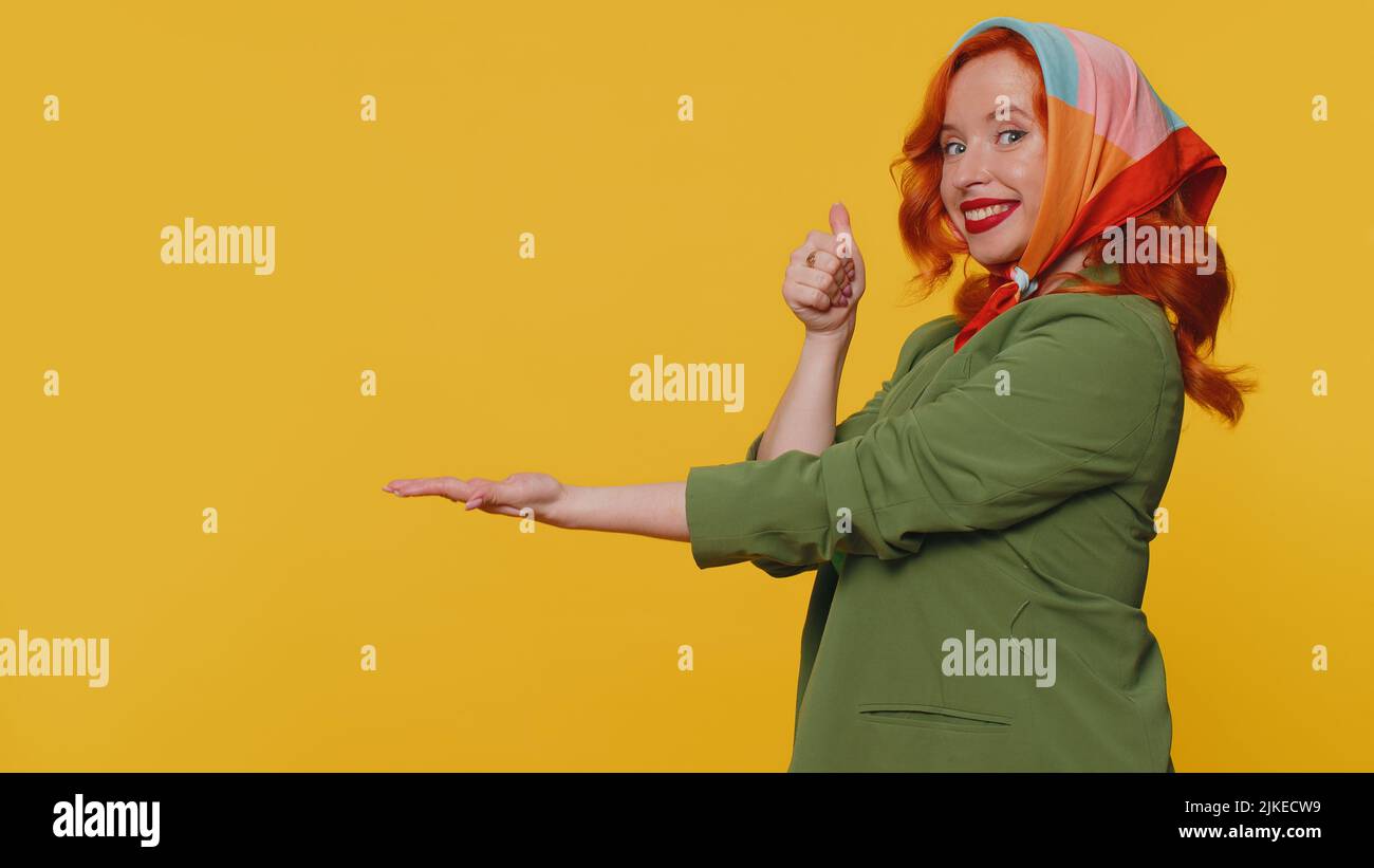 Beautiful redhead woman showing thumbs up, pointing empty place ...