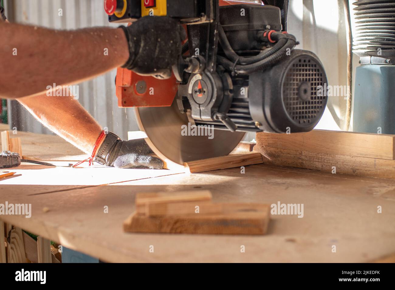 young carpenter working on a circular saw machine cutting a wooden ...