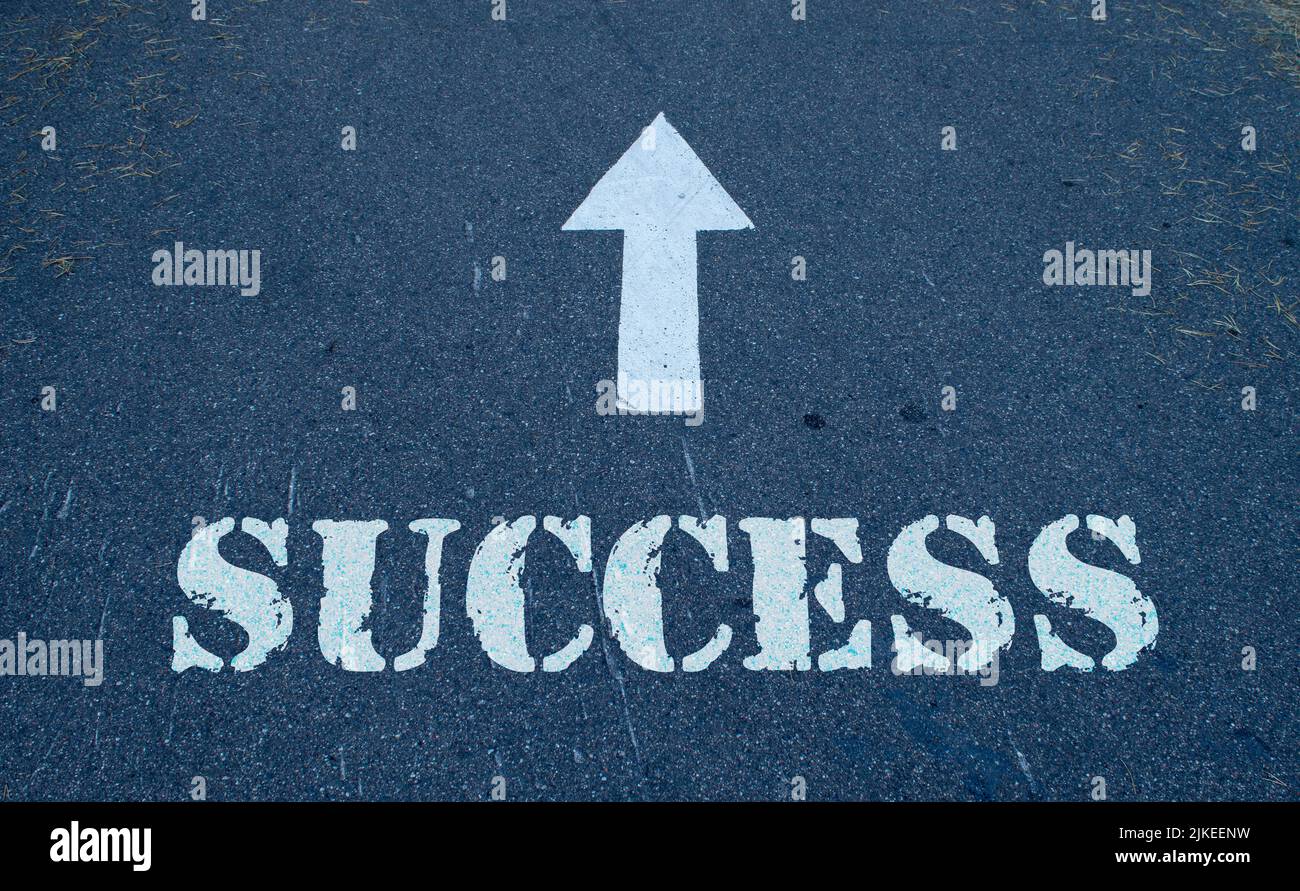 Asphalt road with arrow guideline and success letters painted on the ...