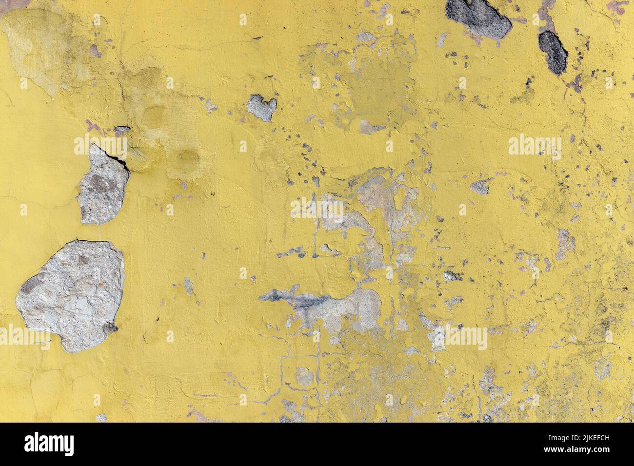 Damaged yellow plaster of a concrete wall, part of a damaged building ...