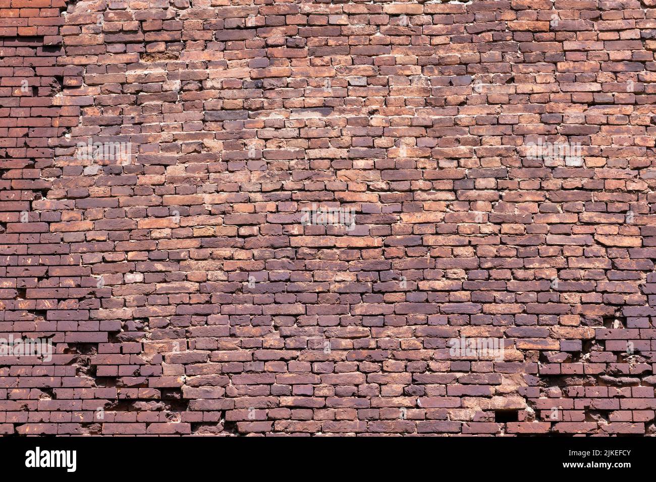 An old brick wall with various damages, the wall is old and made of ...