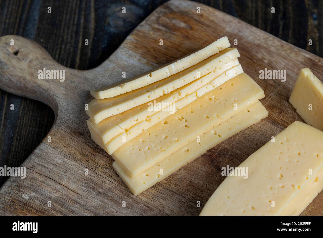 sliced natural cow's milk cheese, fresh yellow milk cheese on a board ...