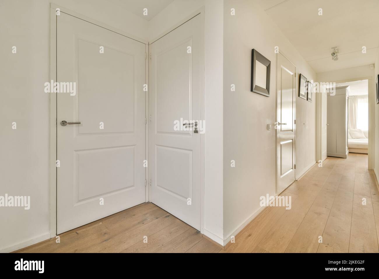 Perspective view of empty narrow hallway with white walls and wardrobe ...