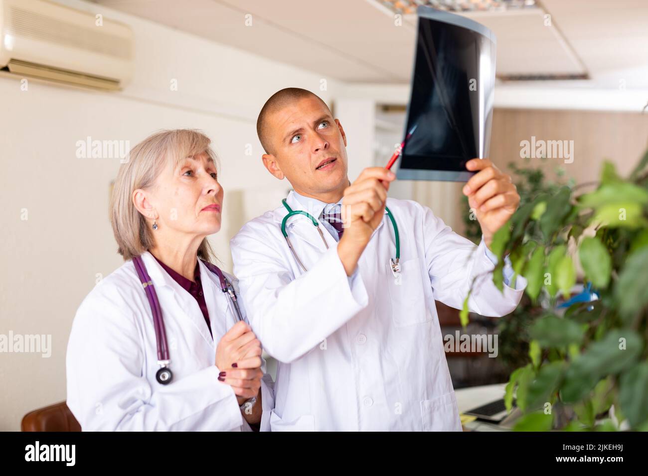 Aged female doctor checking x-ray of patient with male colleague Stock ...