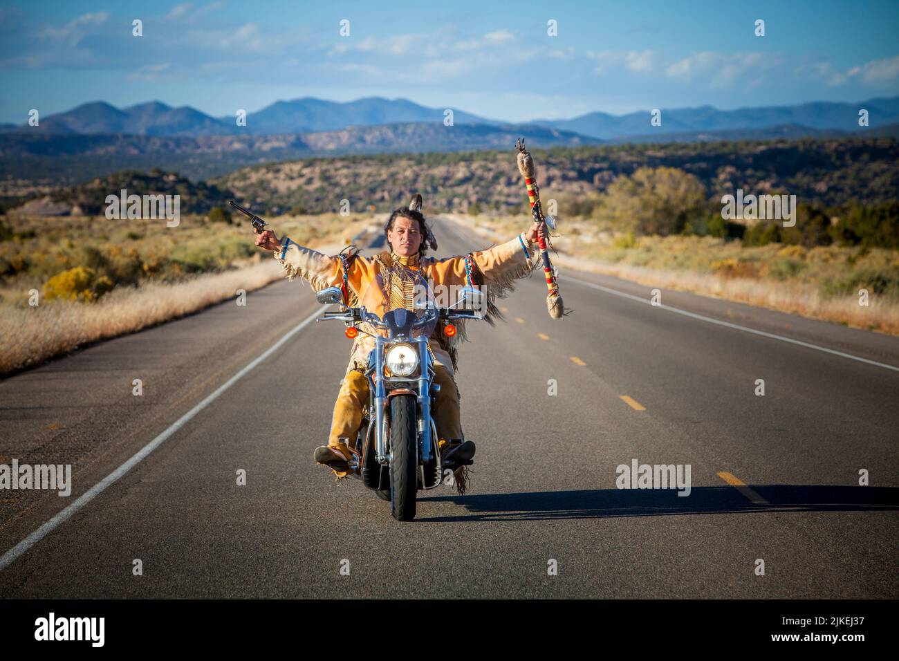 Traditionally dressed Native American man holds coupstick and shoots a ...
