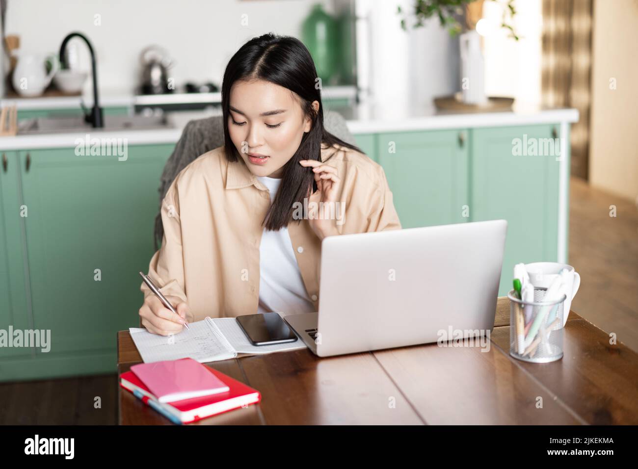Asian girl student doing homework at home. Young woman taking notes ...