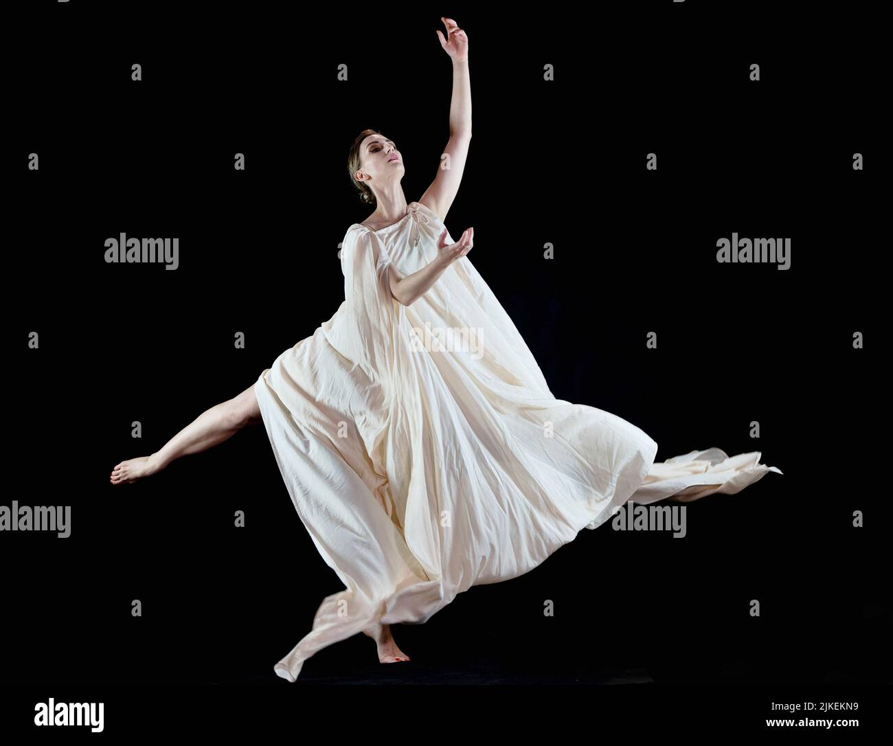 A woman in a white robe on a black background, a dancer, dramatic dance ...