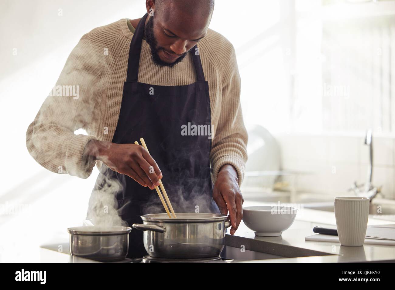 Making magic in the kitchen. a handsome young man cooking on his stove ...