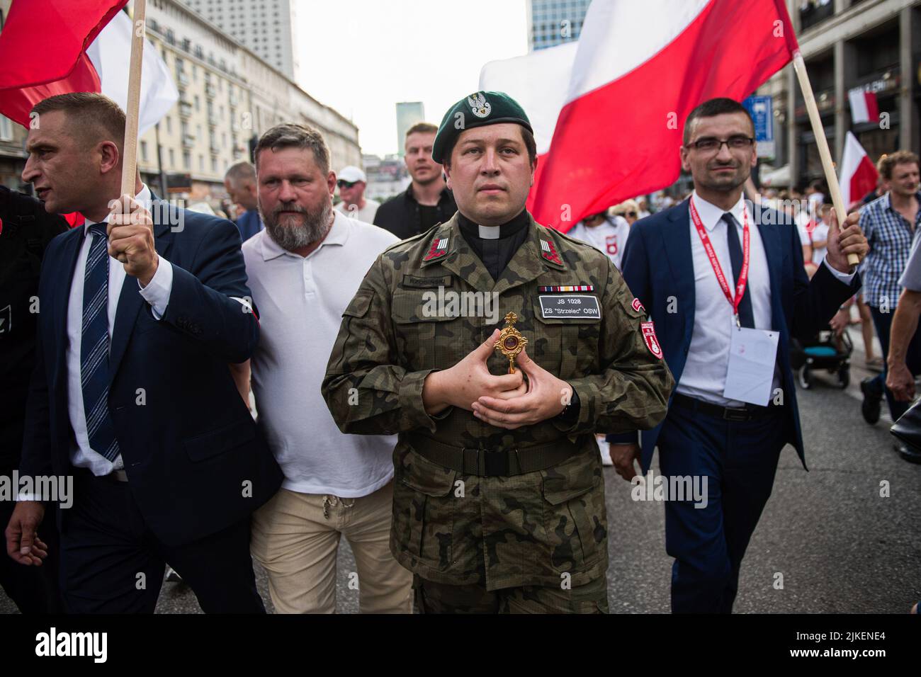 A priest in a military uniform walks in the crowd during the Warsaw ...