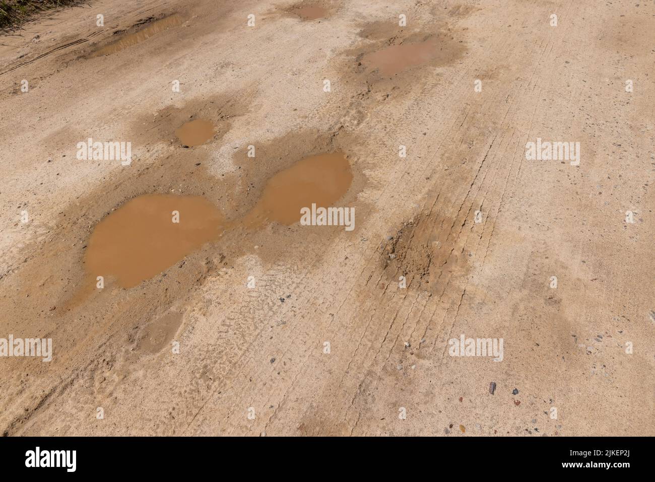 a dirt road with a lot of water holes, puddles on a dirt road after ...