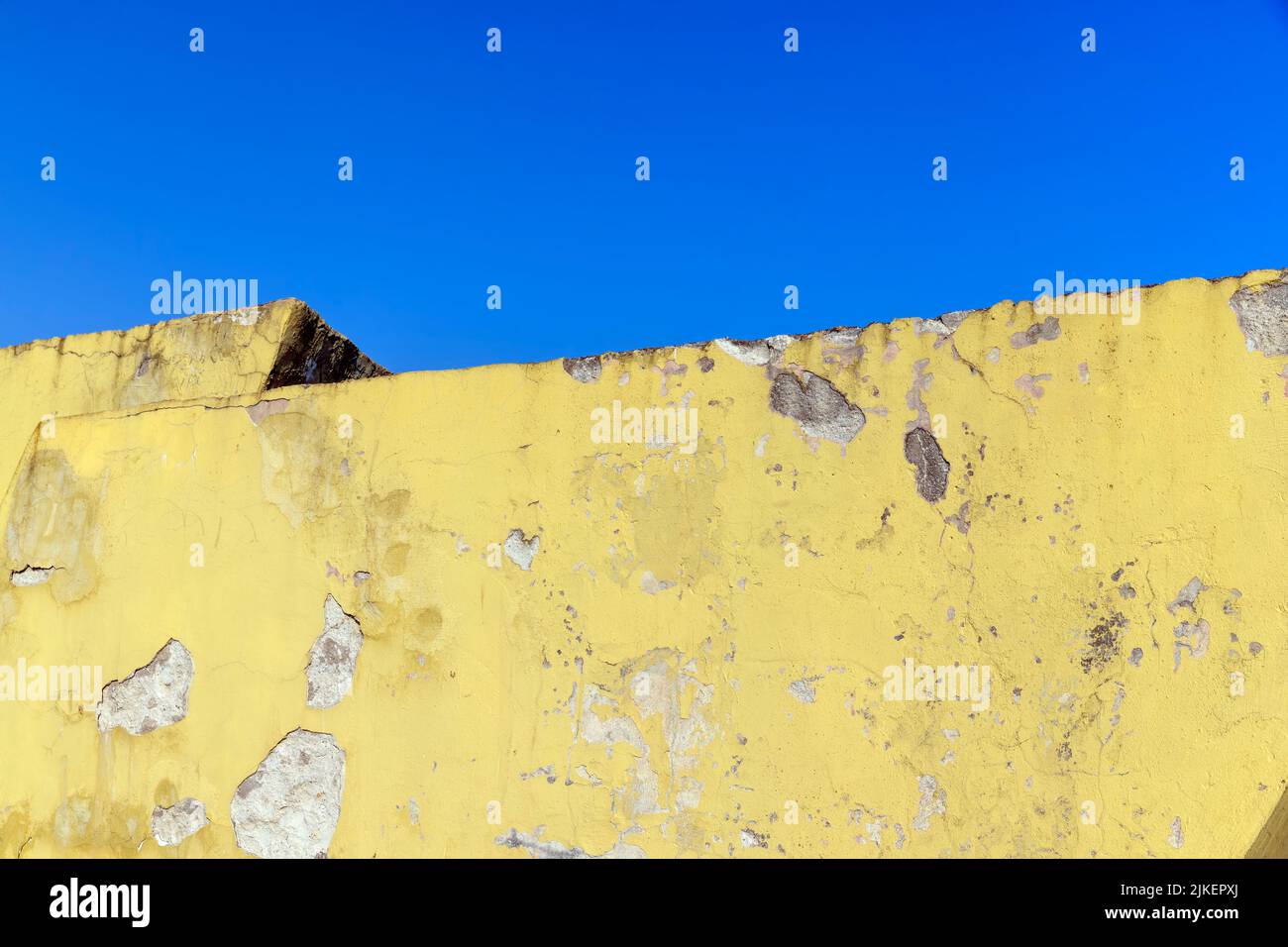 Damaged yellow plaster of a concrete wall, part of a damaged building ...