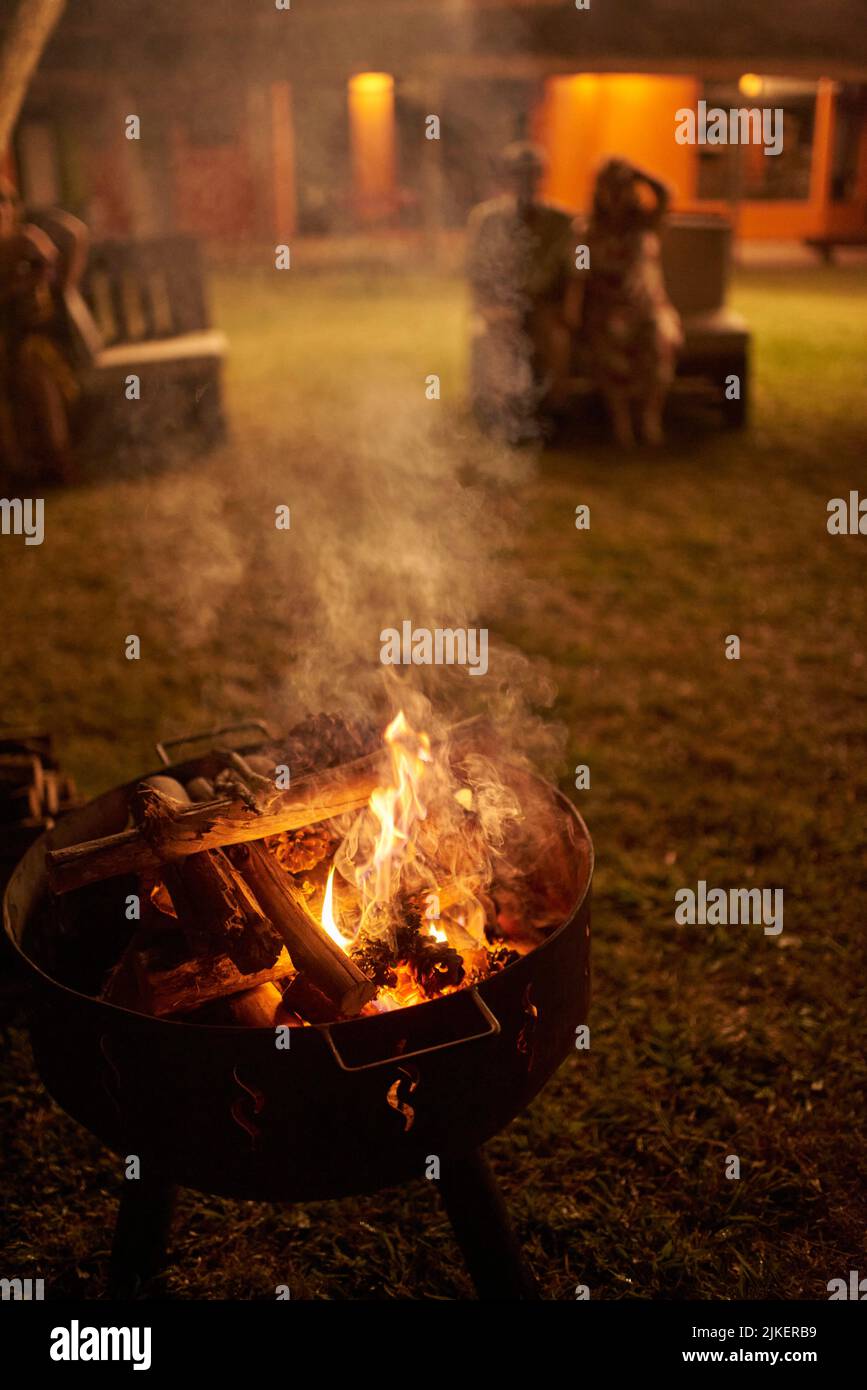 Bonfire lit on a warm summer night, in the background an unrecognizable ...