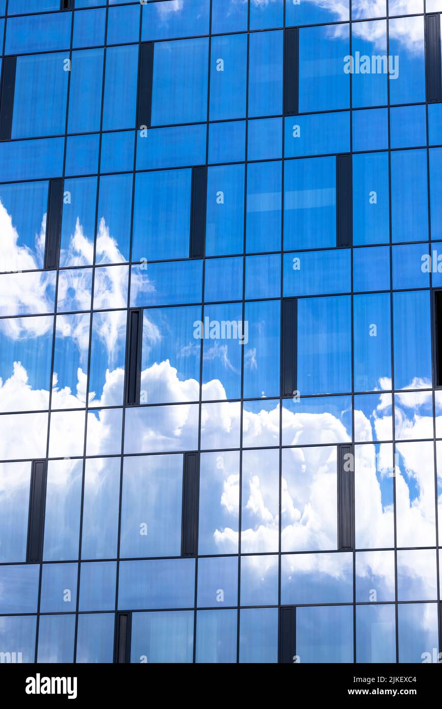 Reflection in the building blue sky with light clouds in windy weather ...