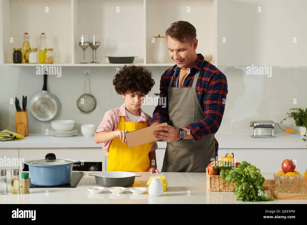Father and son following recipe on tabt computer when cooking dinner ...
