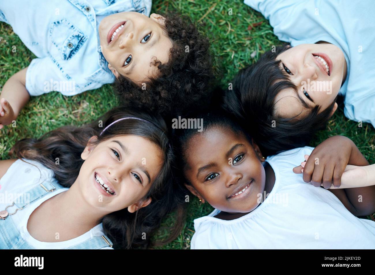 Meet my friends. four adorable kids lying together on the lawn Stock ...