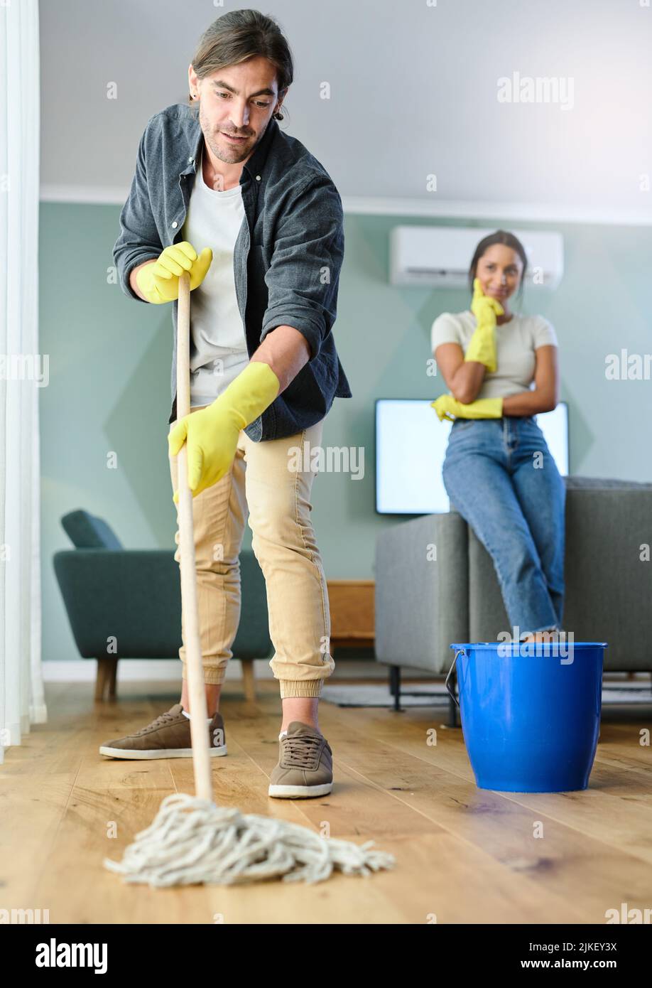 He thinks hes better at cleaning than me. a young man mopping the floor ...
