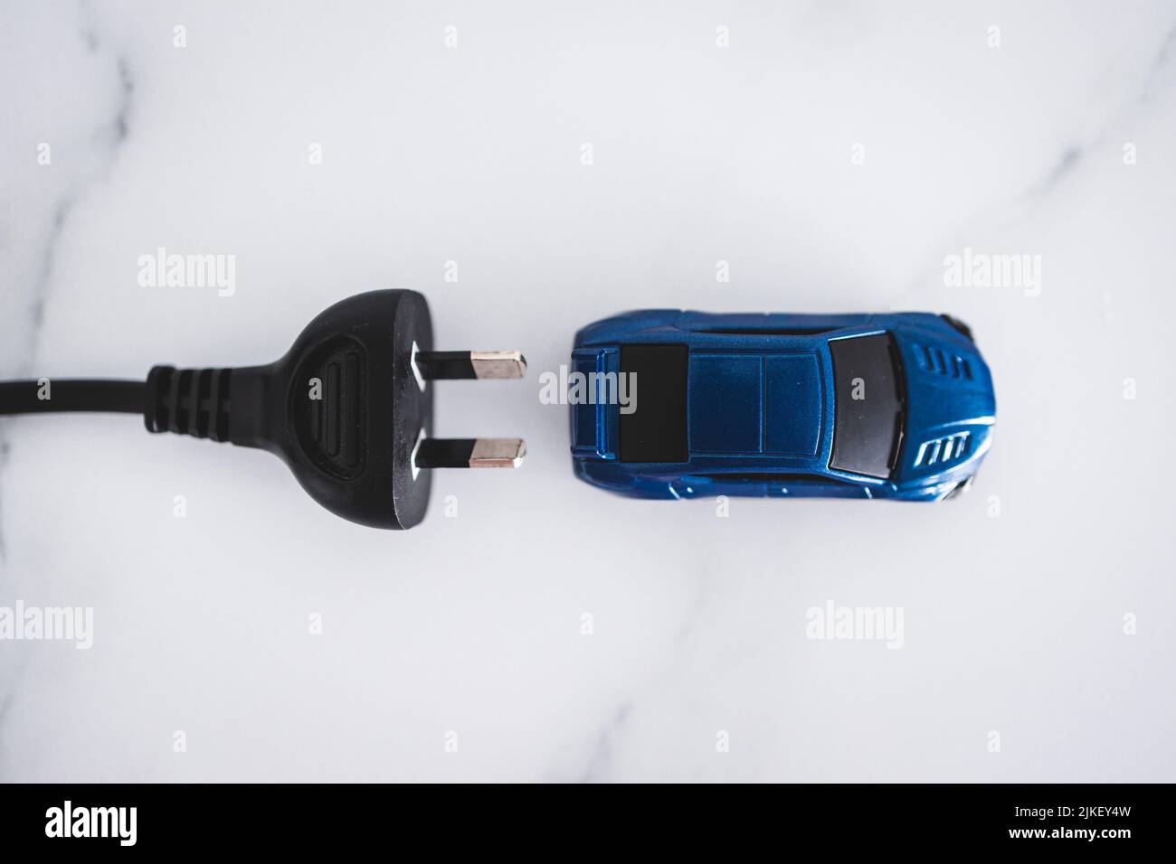 concept of electric or hybrid vehicles, blue toy car with plug behing ...
