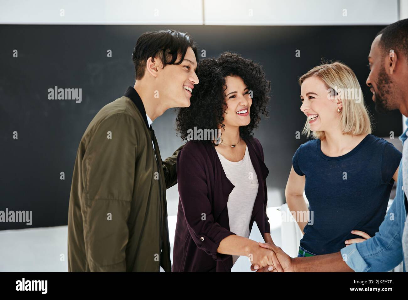 A handshake, agreement and greeting of a group of students in a ...