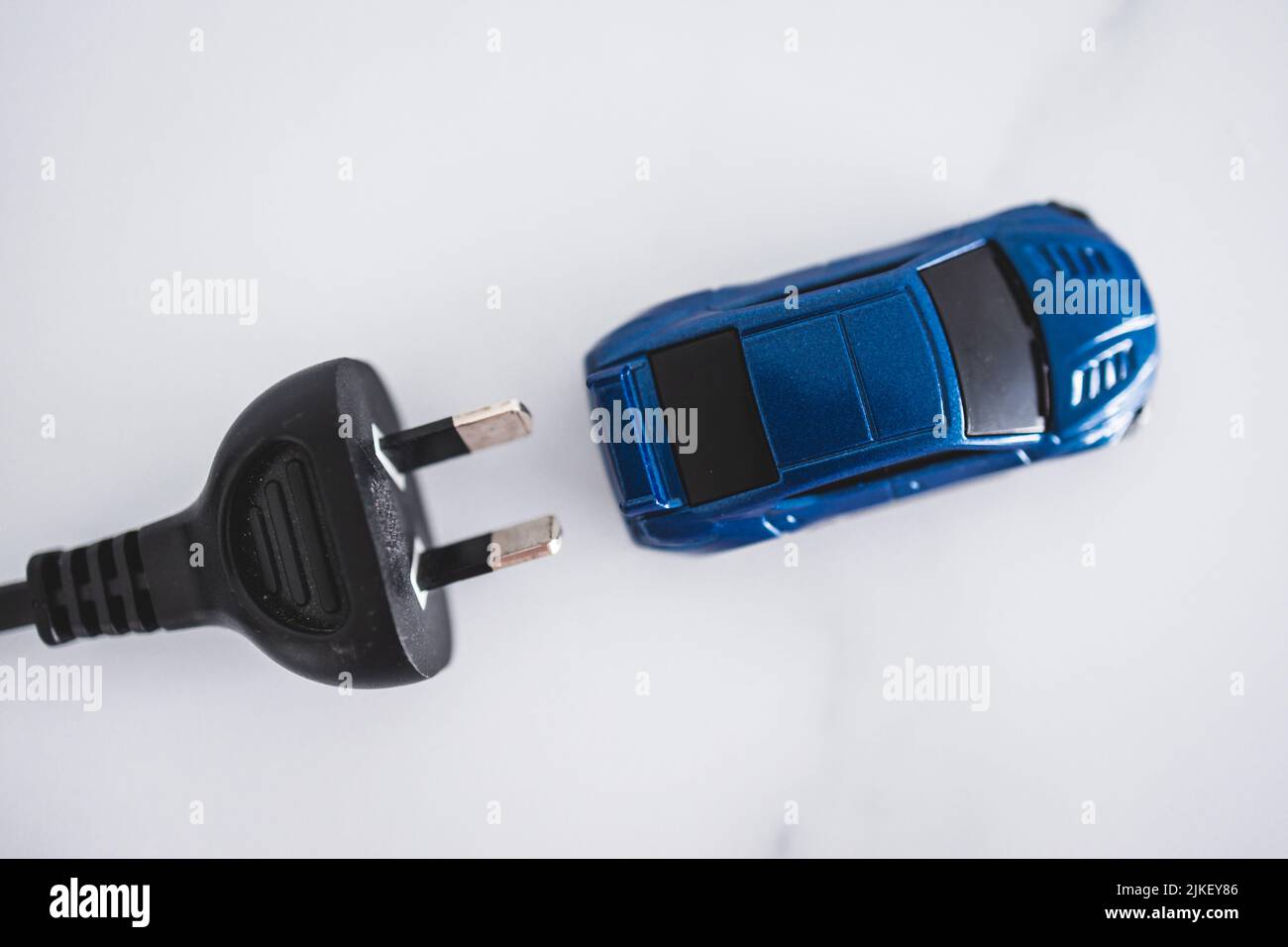 concept of electric or hybrid vehicles, blue toy car with plug behing ...