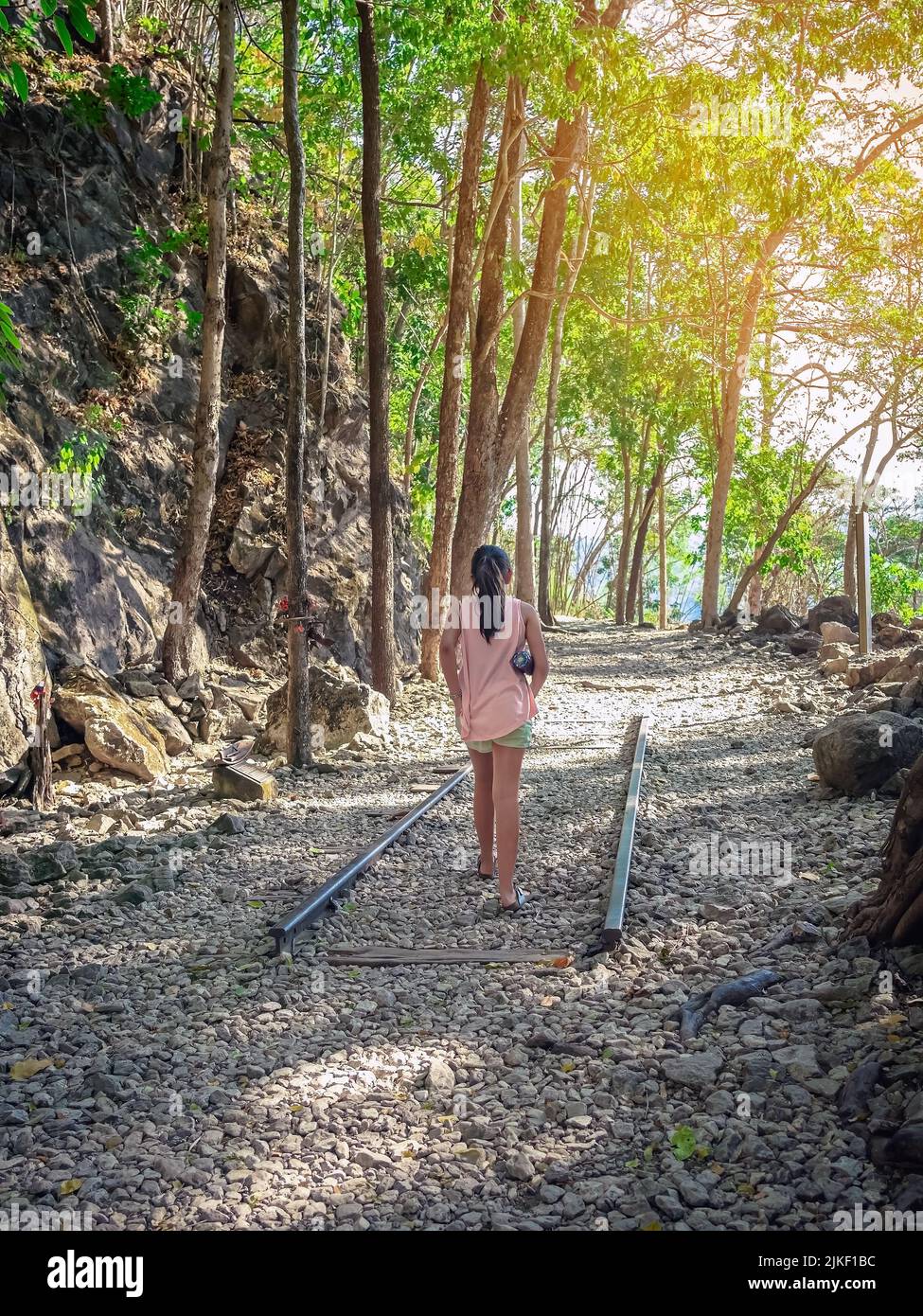 Back View Of Young Girl With Water Bottle Walking Alone In Forest