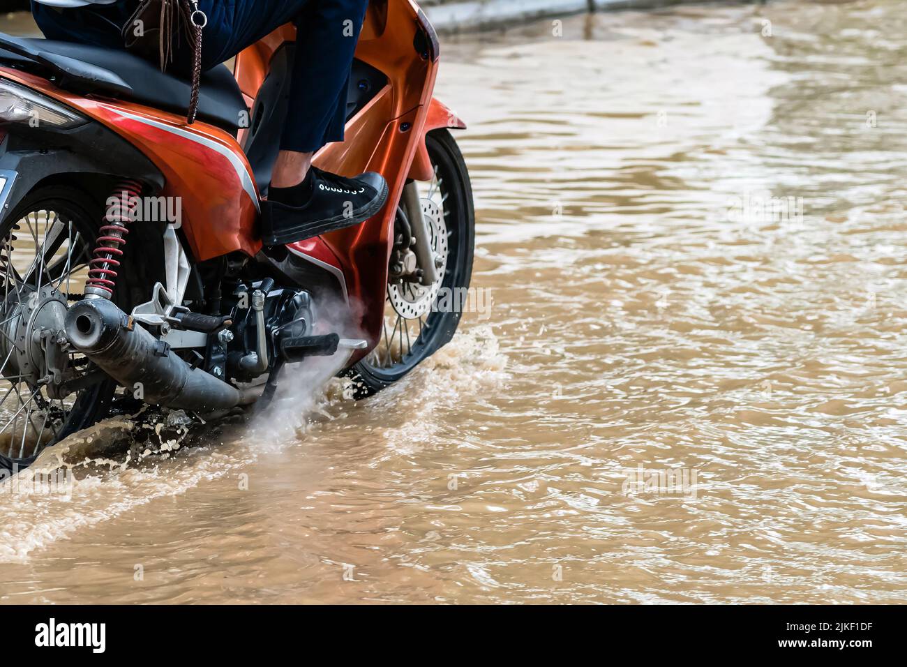 Man ride motorcycle passing through flooded road. Riding motorbike on ...