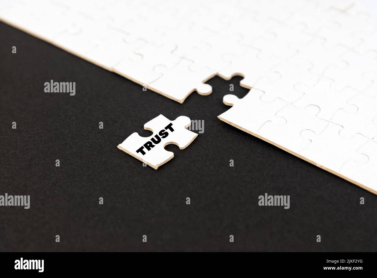 TRUST text on white jigsaw puzzle with missing piece on black ...