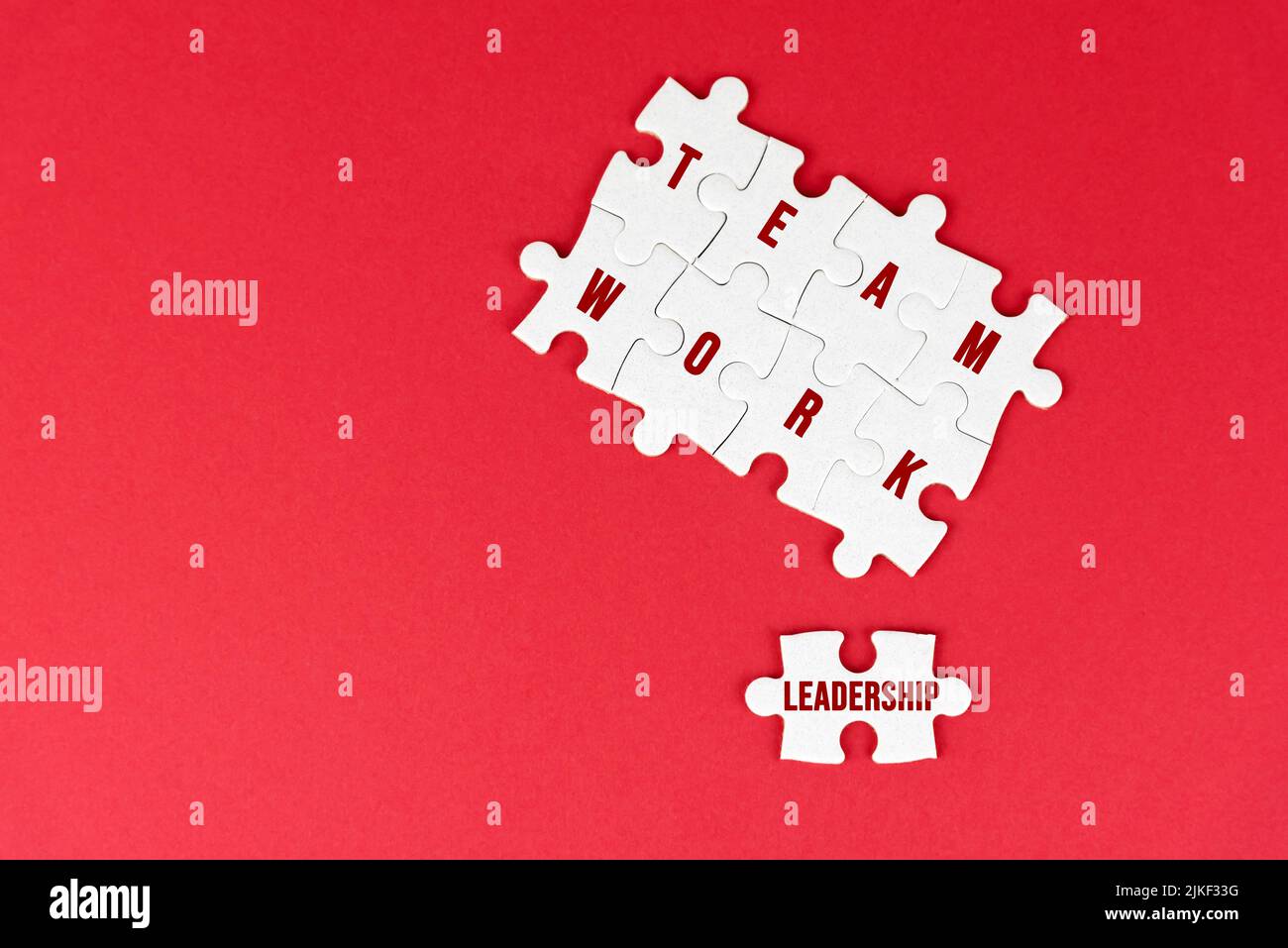 Teamwork and leadership concept with text on white jigsaw puzzle with ...