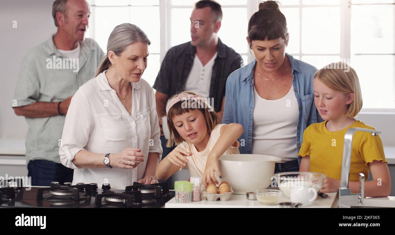 Cracking some eggs to bake a cake. a family baking together in the ...