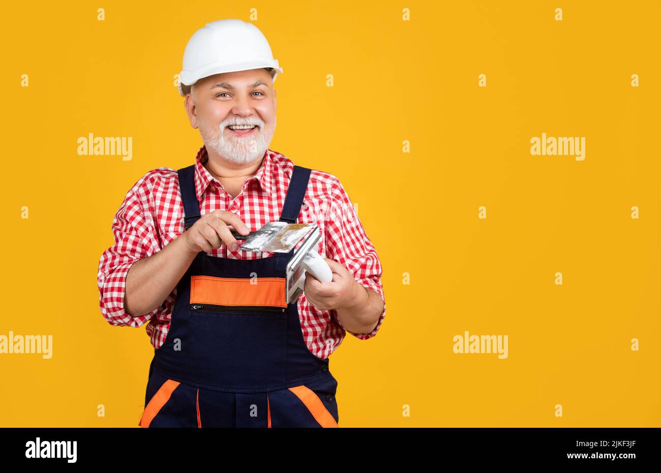 happy mature man plasterer in helmet on yellow background Stock Photo ...