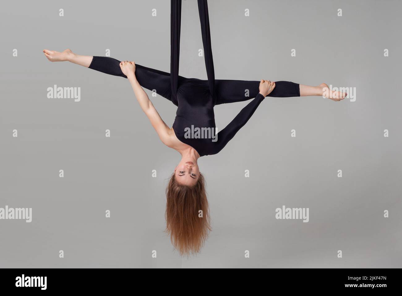 Beautiful girl in a black sport suit is performing an acrobatic ...