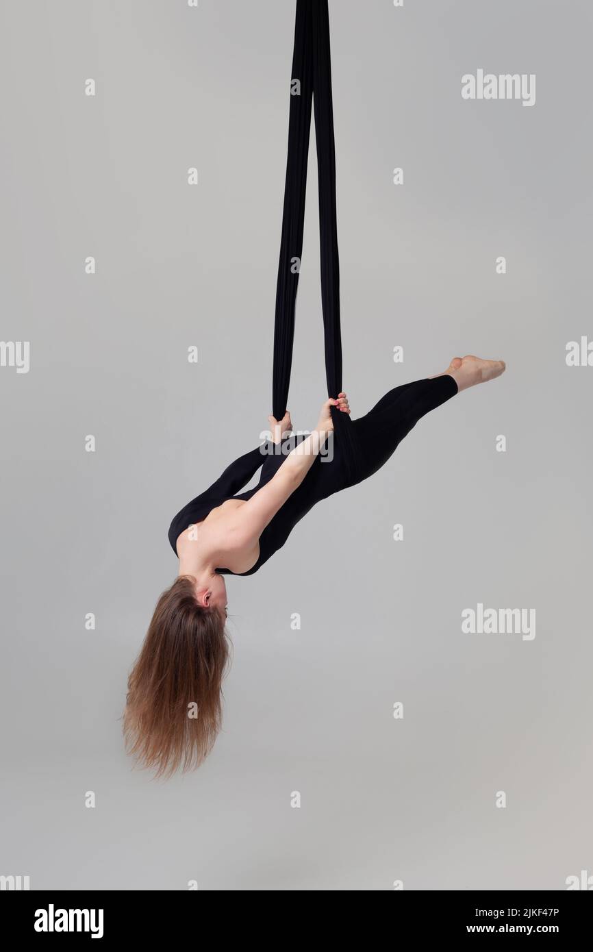 Beautiful girl in a black sport suit is performing an acrobatic ...