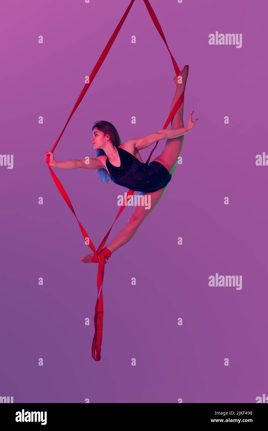 Beautiful girl in a black swimsuit is performing an acrobatic elements ...