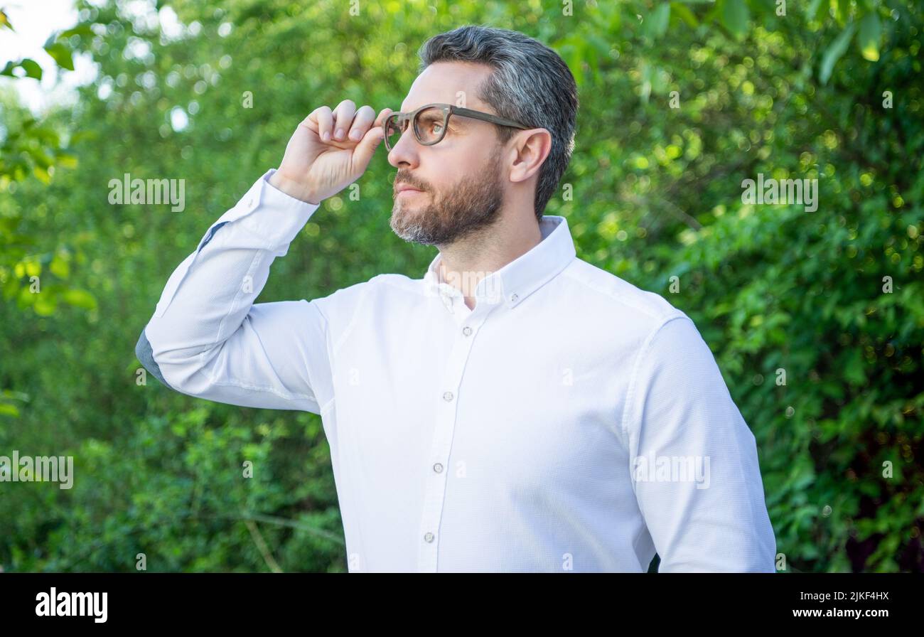 Professional man looking into distance in eyeglasses natural background ...