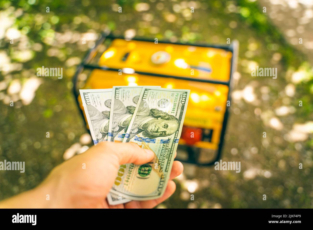Buying a gasoline generator for dollars. A hand holds three one hundred ...