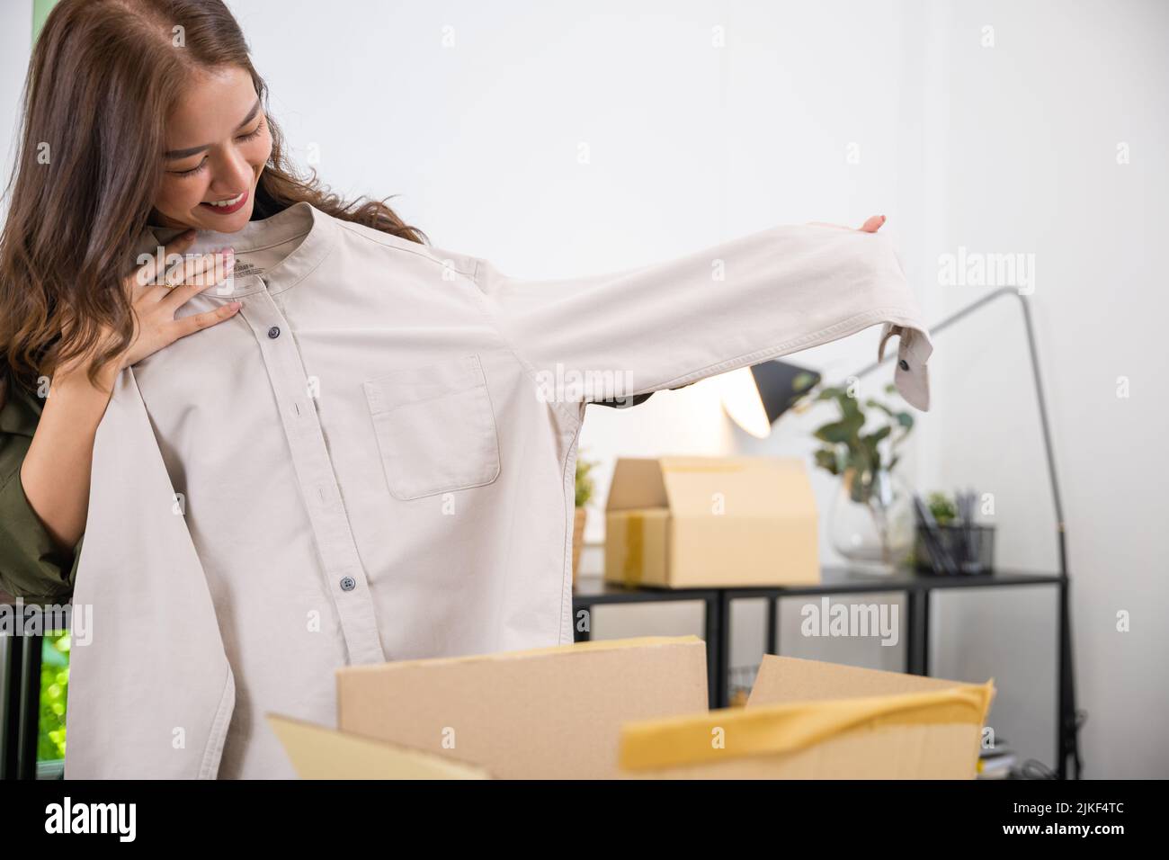 Happy Asian woman customer opening box and shirt against body new ...