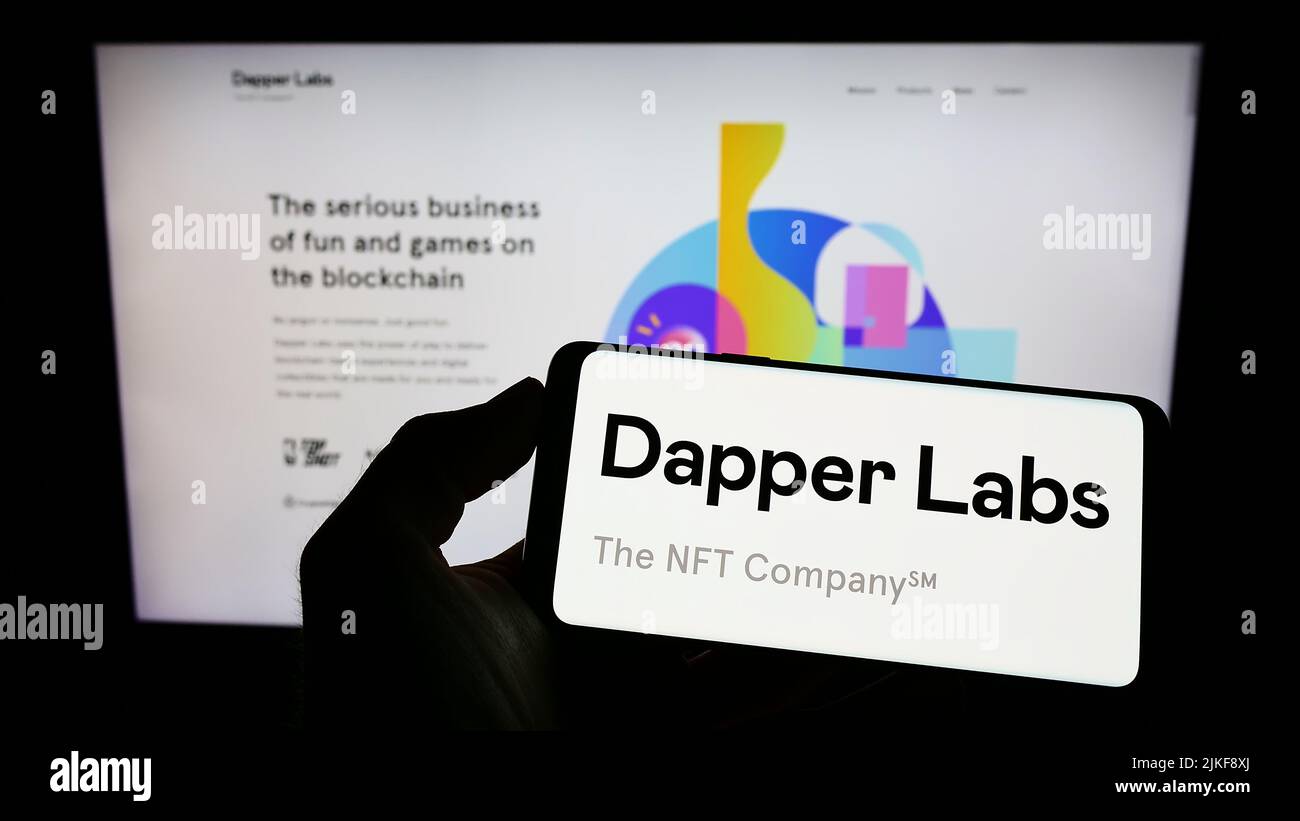 Person holding mobile phone with logo of Canadian blockchain company Dapper Labs Inc. on screen ...