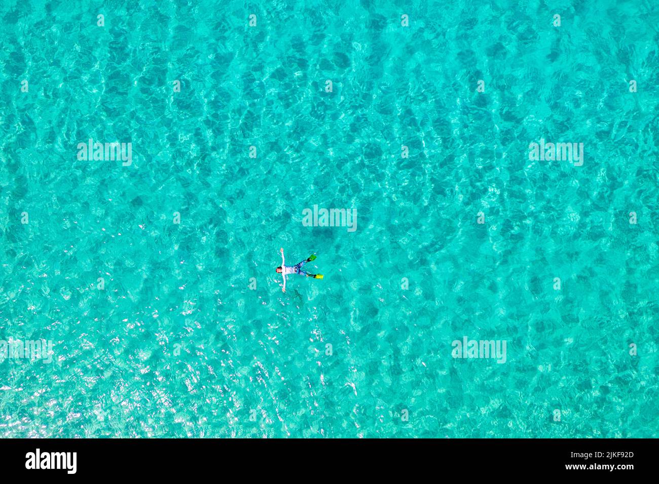 Aerial view of a boy swimming in a turquoise water in a bay near Veli ...