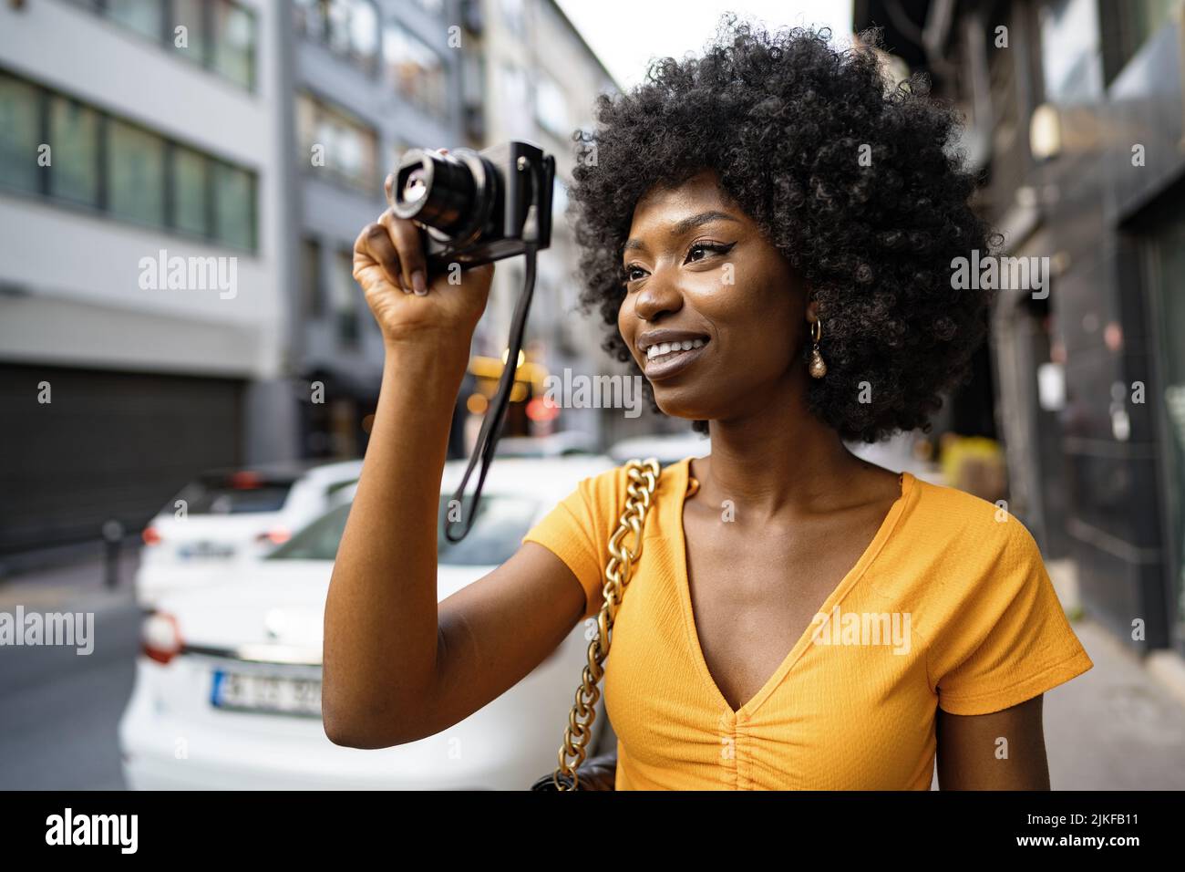 Smiling African american woman using professional camera at a street ...