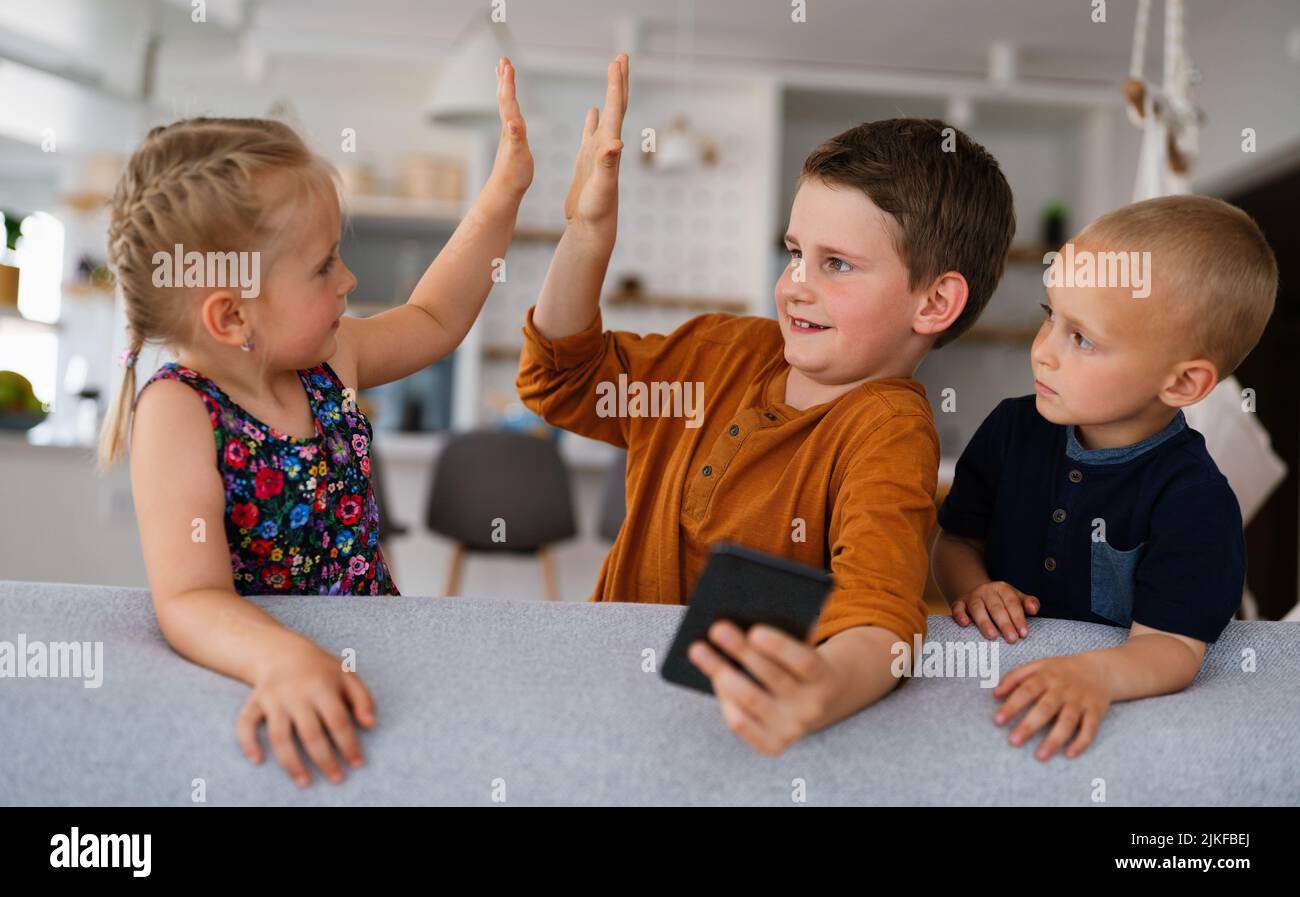 Portrait of children playing on mobile phone together at home. Internet ...