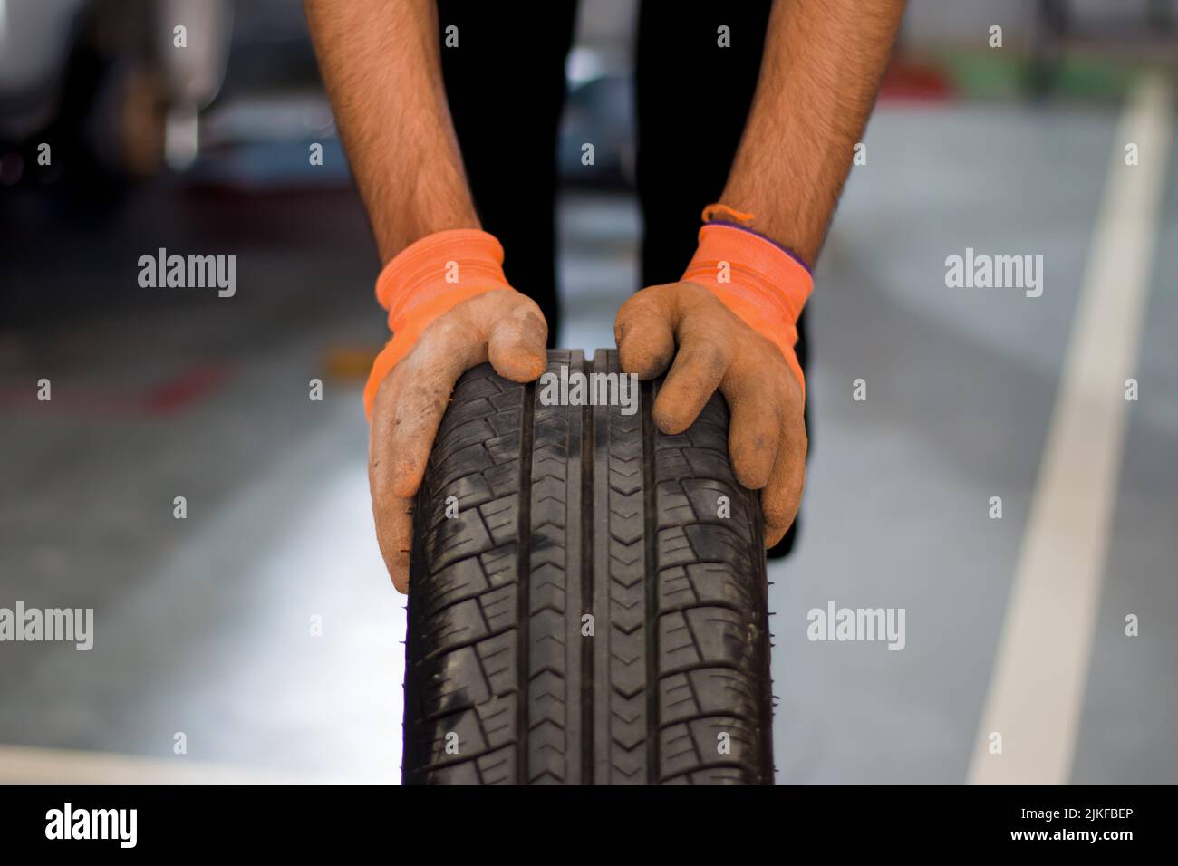 Pakistani or Indian or South Asian car mechanic rolling tire with hands ...