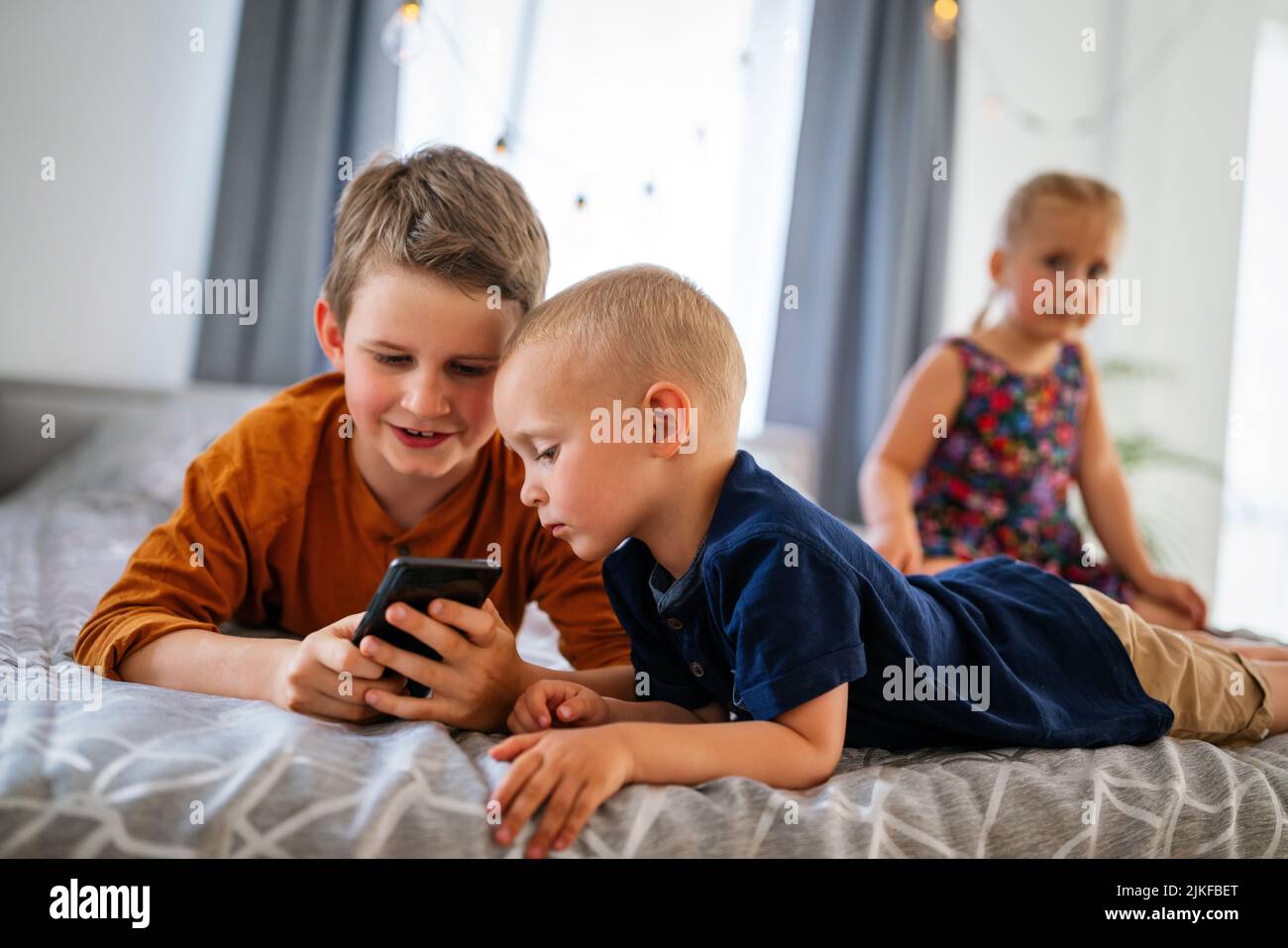 Portrait of children playing on mobile phone together at home. Internet ...