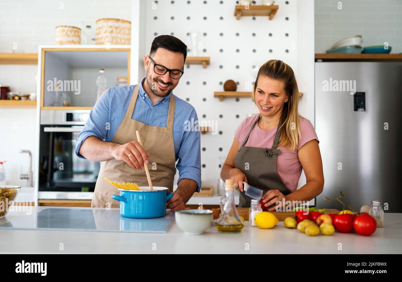 Young happy couple is enjoying and preparing healthy meal in their ...