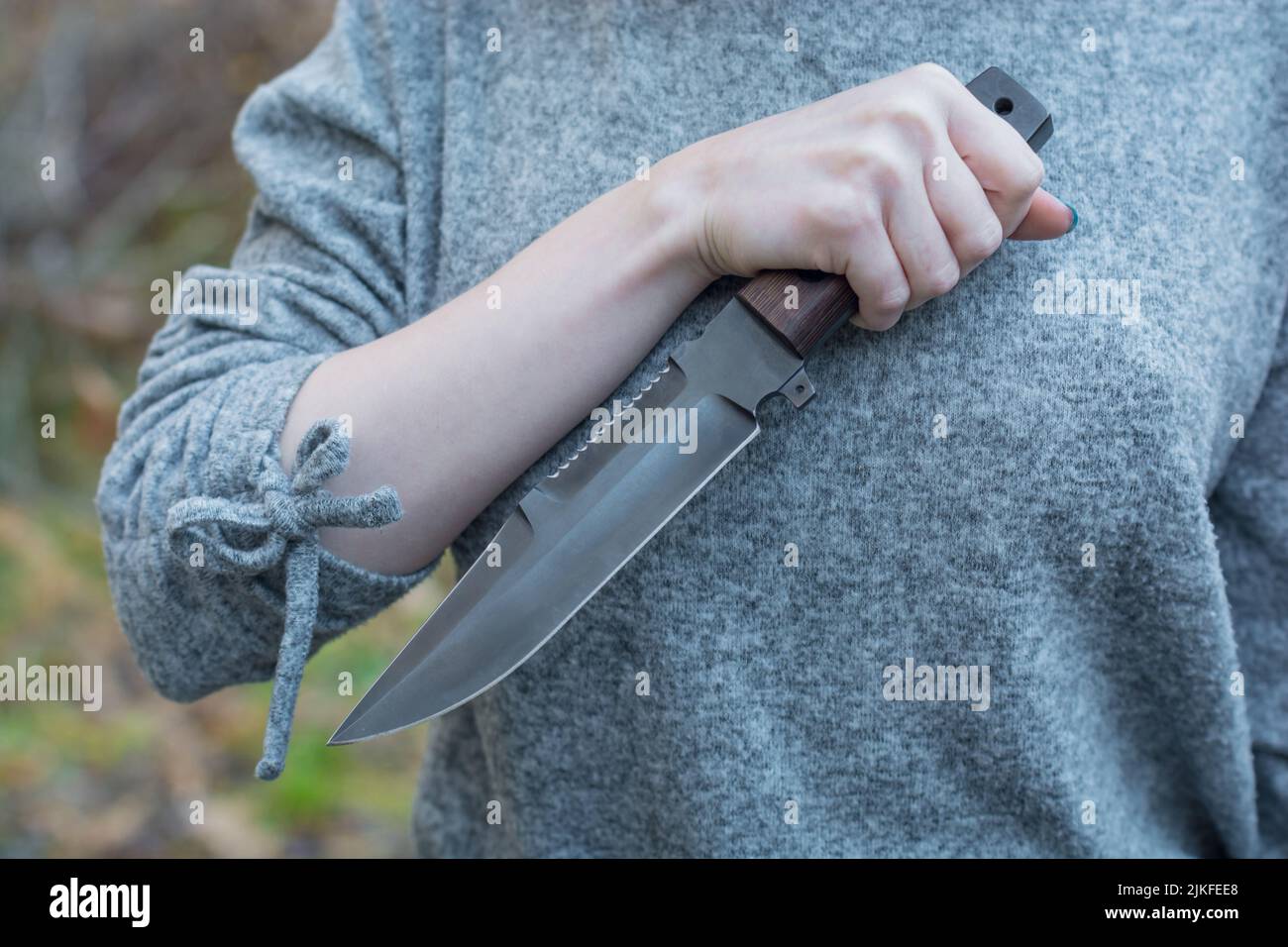 The close-up partial view of a woman holding a hunting knife in her ...